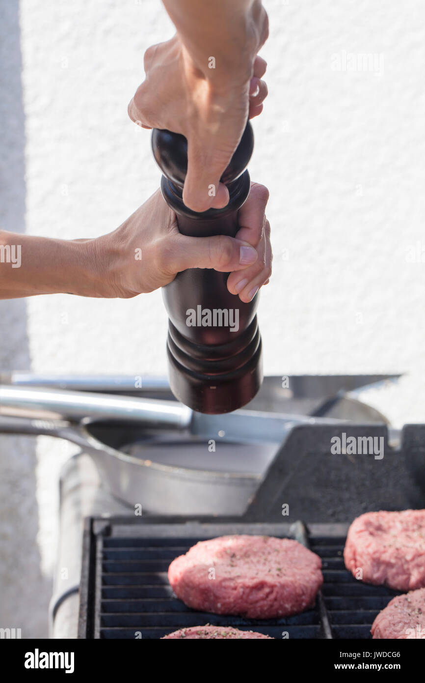 Hamburgers being seasoned and grilled on an outdoor barbecue Stock ...