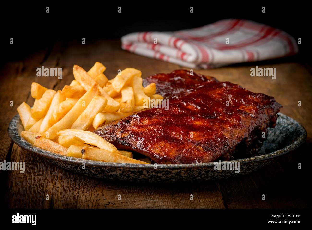 Slow cooked pork baby back ribs with french fries Stock Photo - Alamy