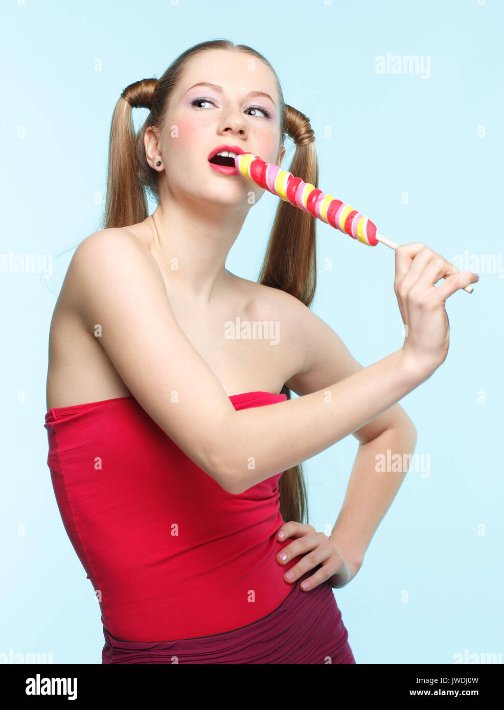 Beautiful playful young freckled singing girl with lollipop on blue ...