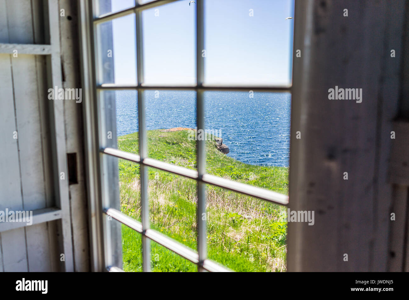 Looking through old window of house with cliff and ocean view in ...