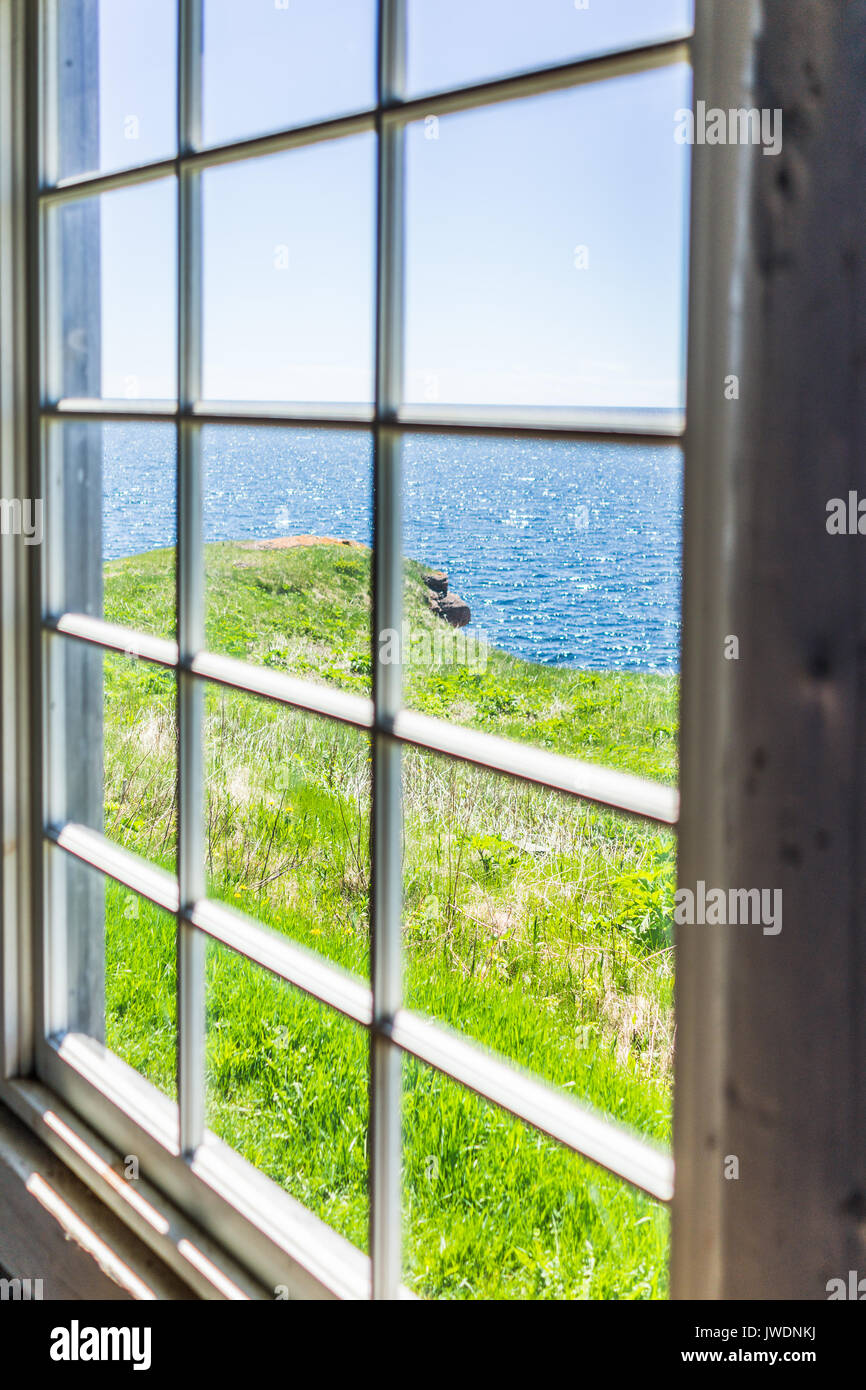 Looking through old window of house with cliff and ocean view in ...