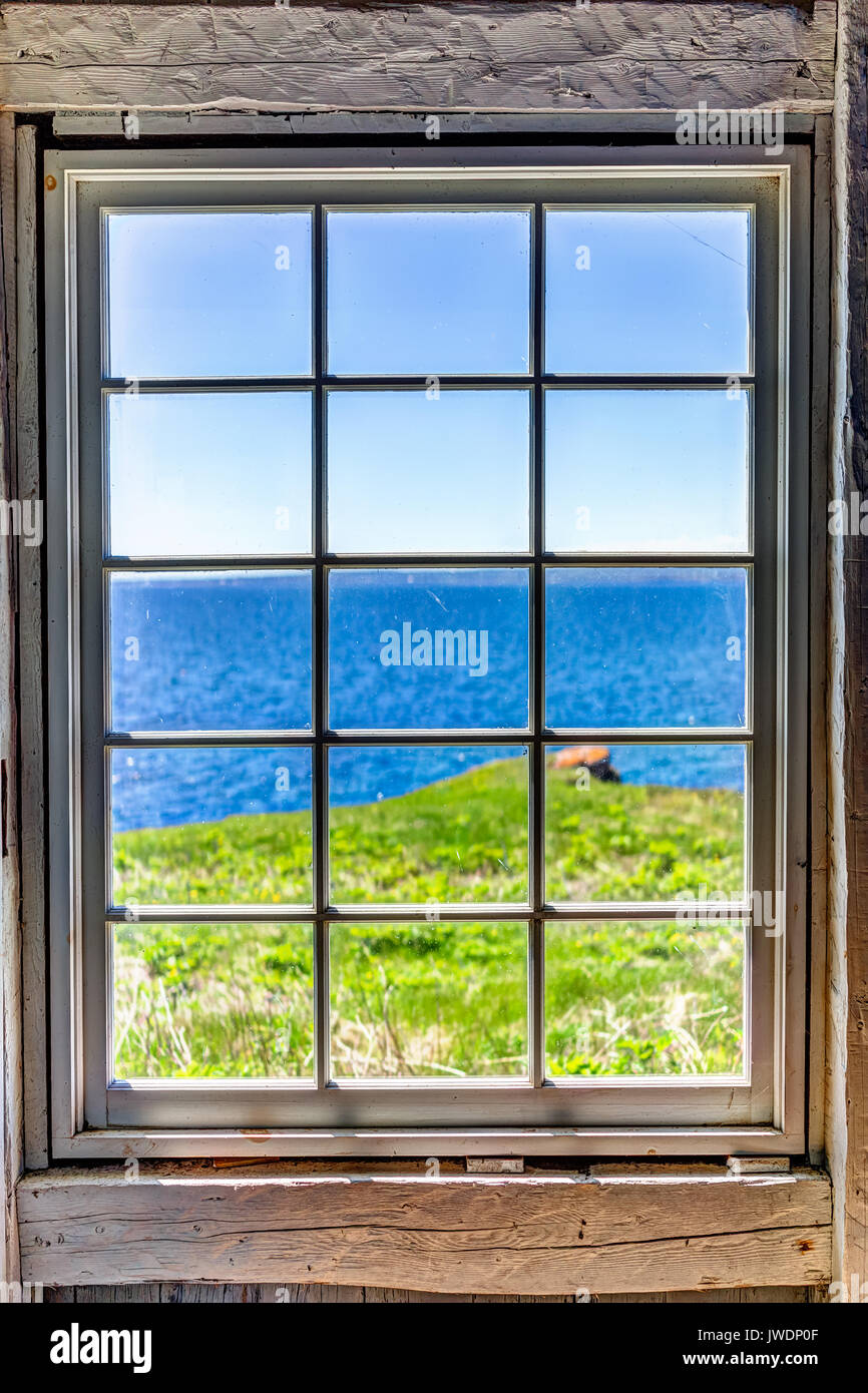 Looking through old window of house with cliff and ocean view in ...