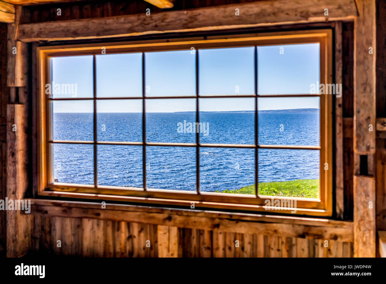 Looking through old window of house with cliff and ocean view in ...