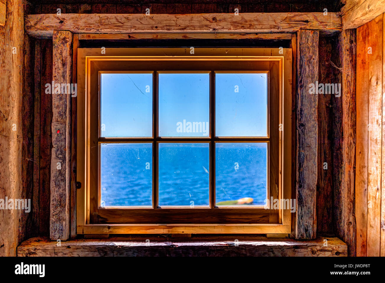 Looking through old rustic window of house with ocean view in ...