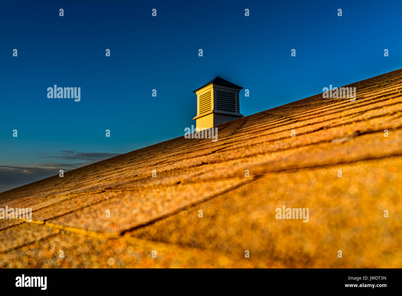 Sunrise with dark sky and illuminated roof with chimney closeup showing ...