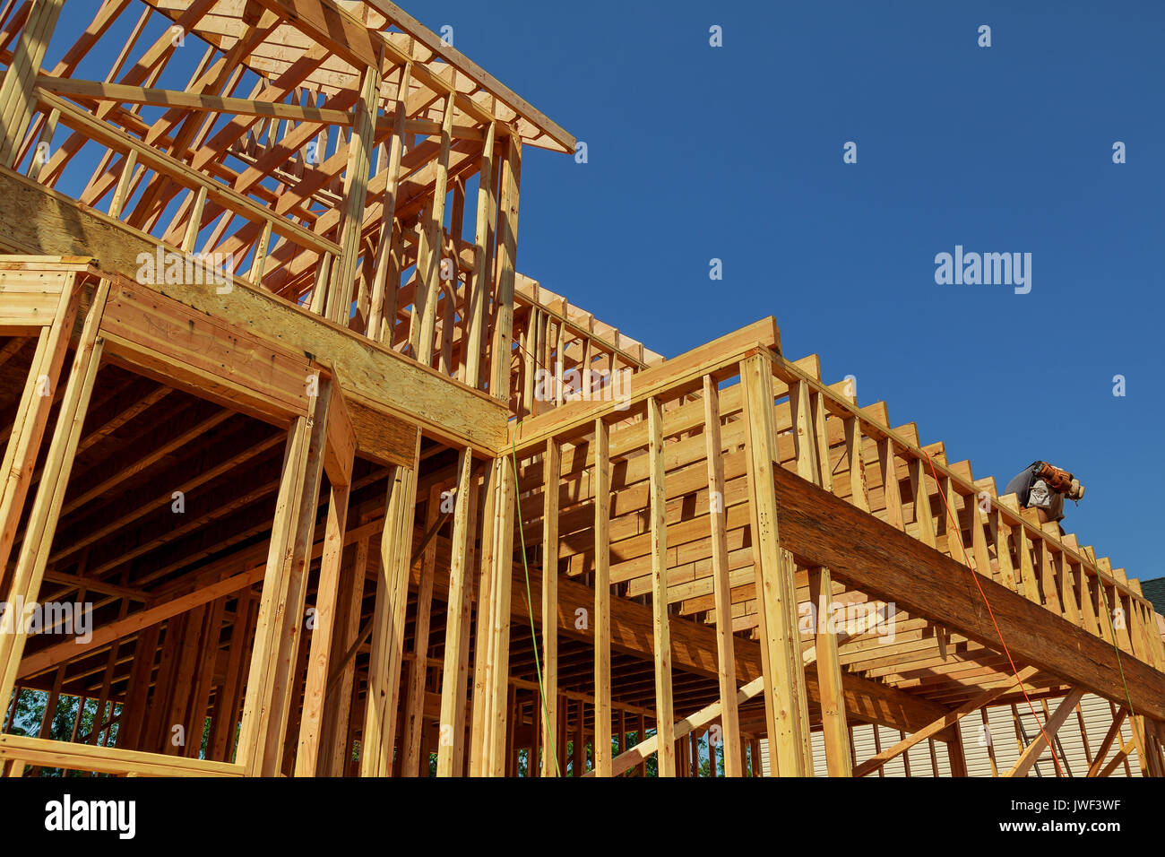 New residential construction home framing against a blue sky and sun ...