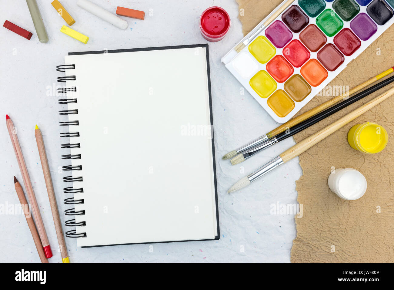 artist work tools on table: watercolor, paintbrushes and pencils with ...