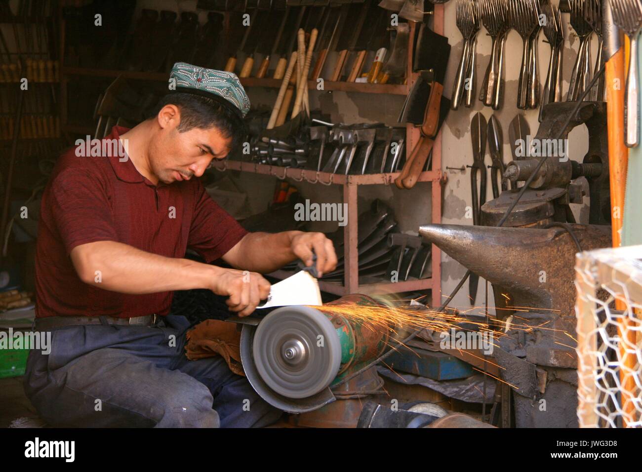 Metal smith at work on his grinder in old town Kashgar Stock Photo - Alamy