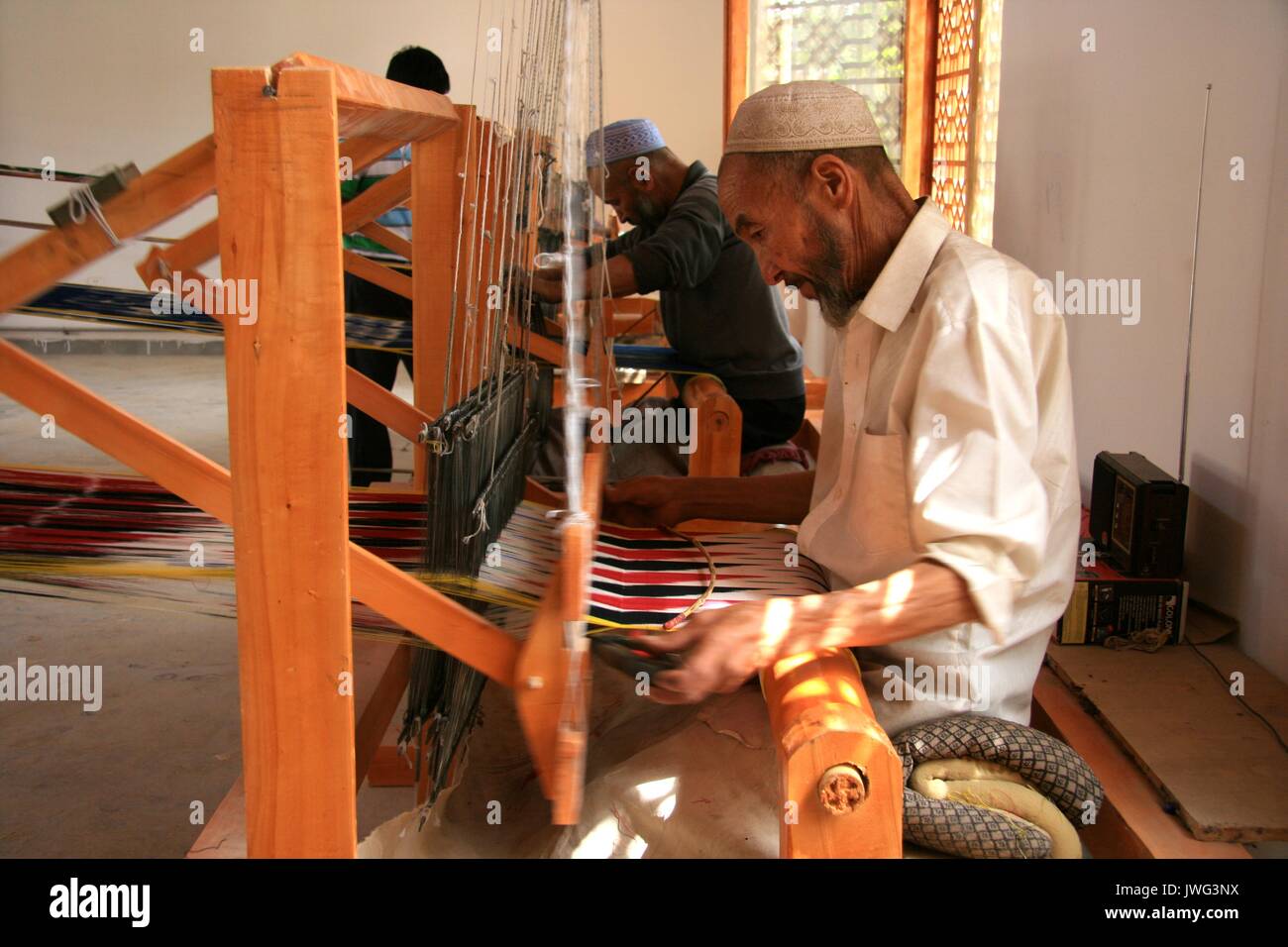 Men weaving colourful silk cloth ad rugs at the Atlas Silk Factory ...