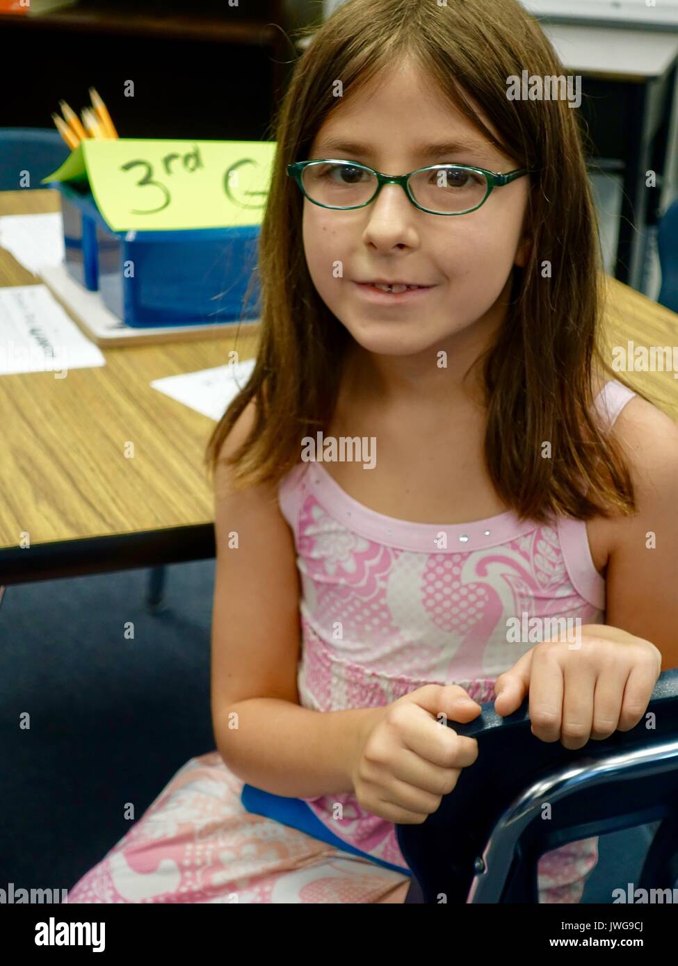 Facing camera, back to school. Smiling, third grade girl with glasses ...