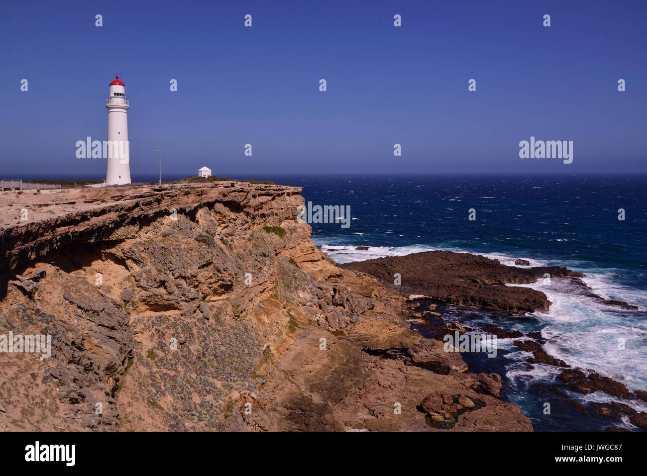 The lighthouse at Cape Nelson is looking over the waves rolling onto ...
