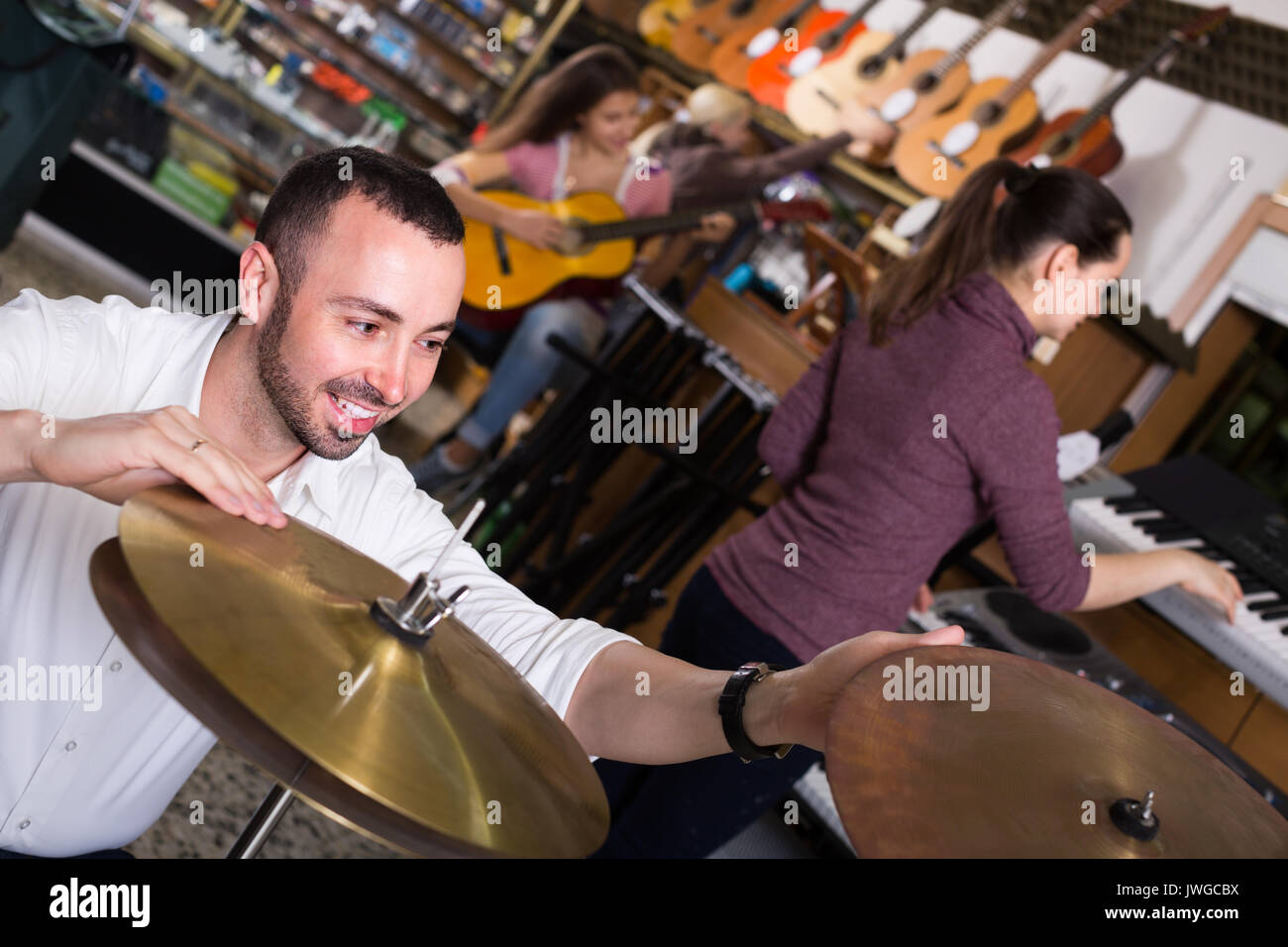 Positive guitarists making musical performance in store and smiling ...