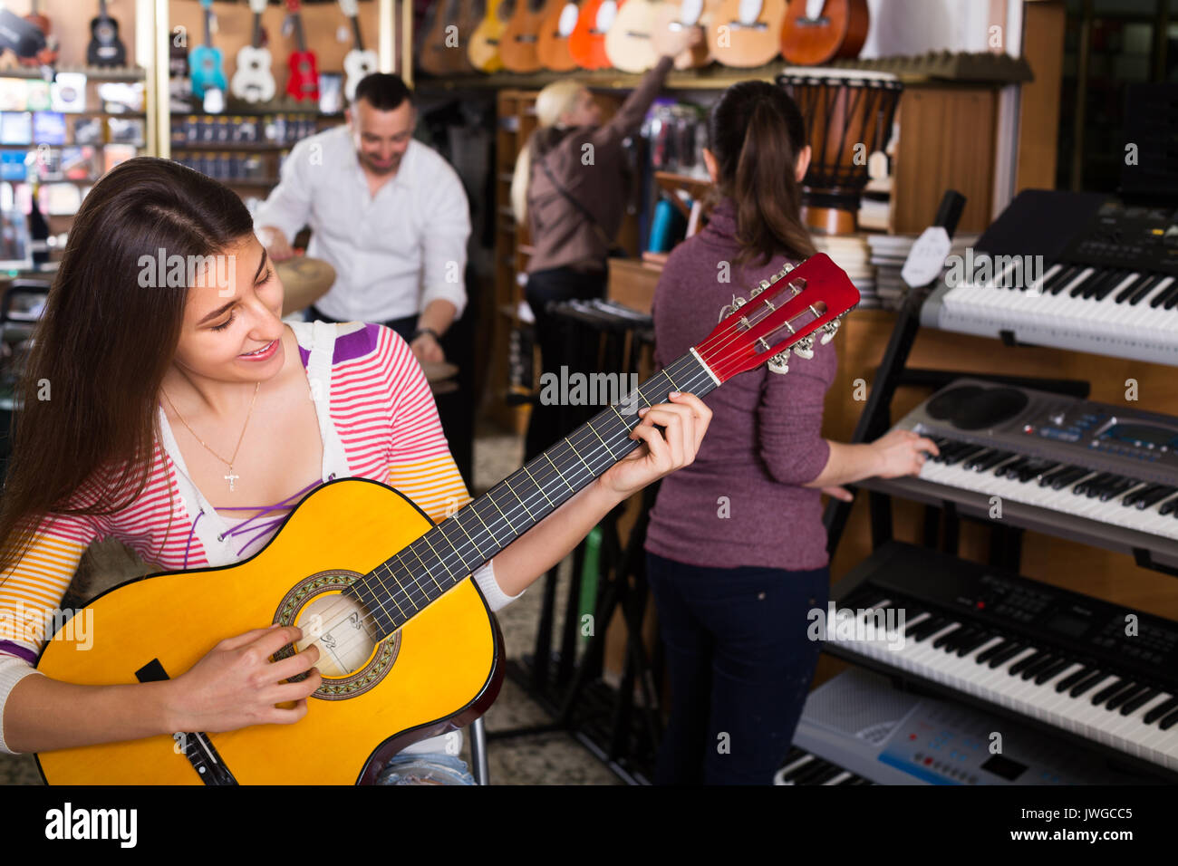 Smiling people looking at professional musical instruments in store ...