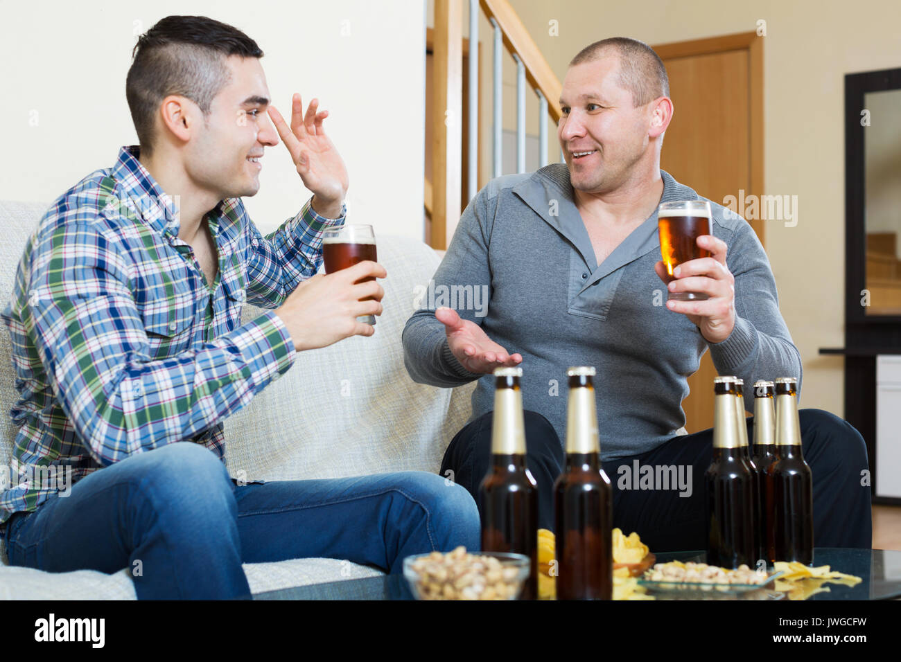Two colleagues sitting with beer after work indoor Stock Photo - Alamy