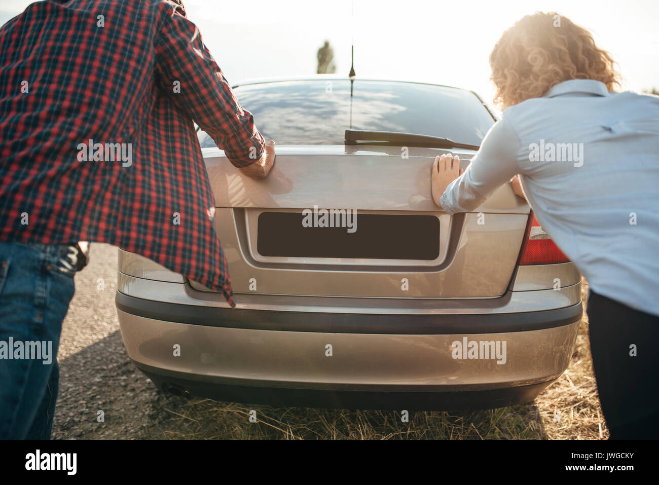 Man and woman pushing a broken car down the road, back view. Vehicle ...