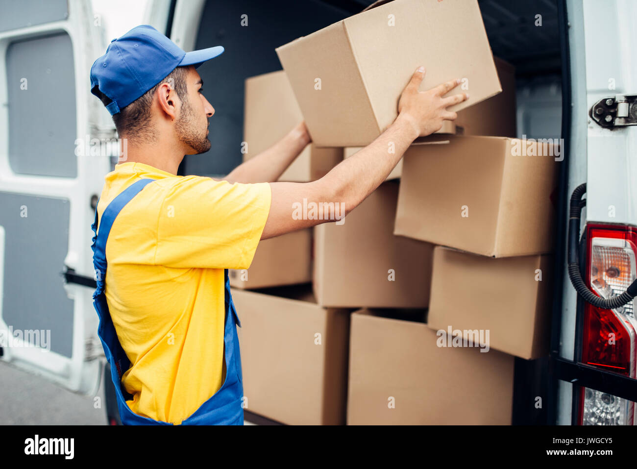 Cargo delivery service, male courier in uniform with box in hand ...