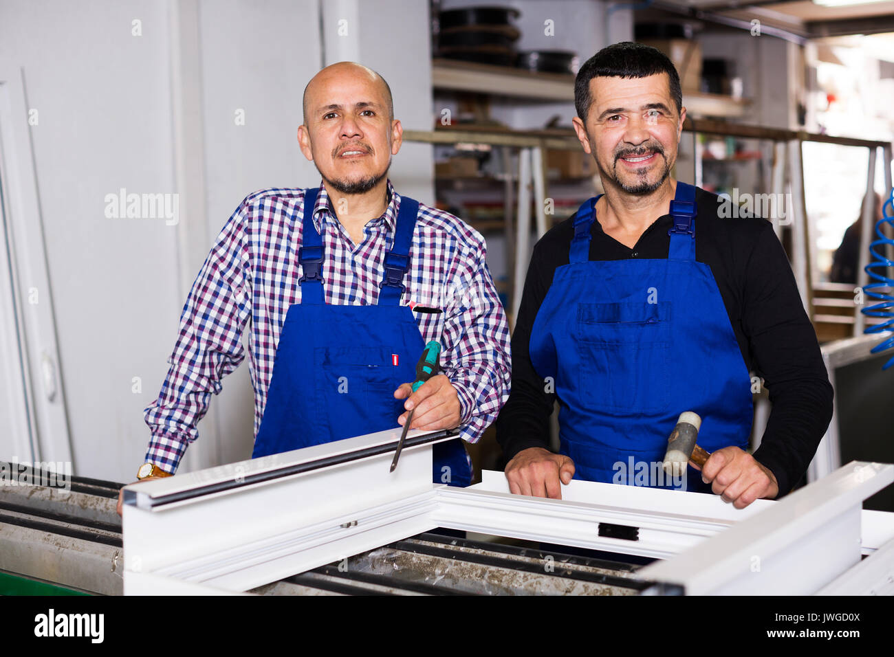 Professional workers with PVC profiles and windows at factory Stock ...