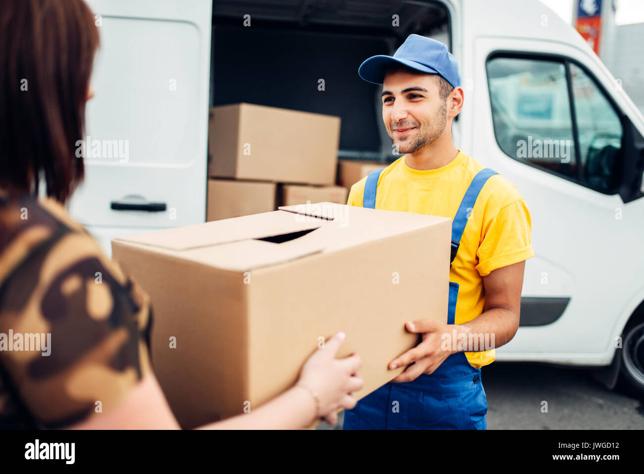 Cargo delivery service, male courier in uniform gives a parcel to the ...