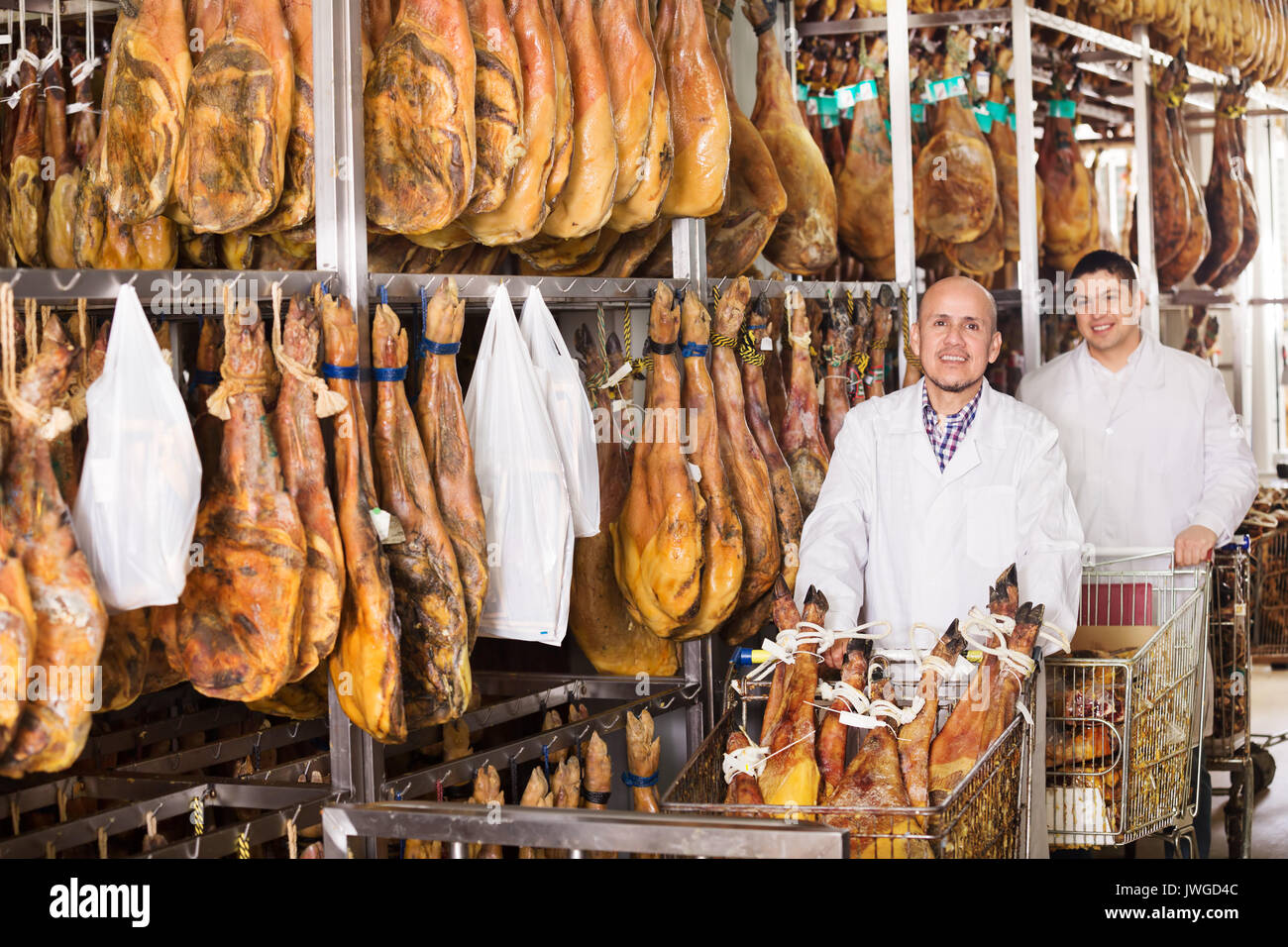 Mature butcher and his assistant with the jamon joints at the meat ...