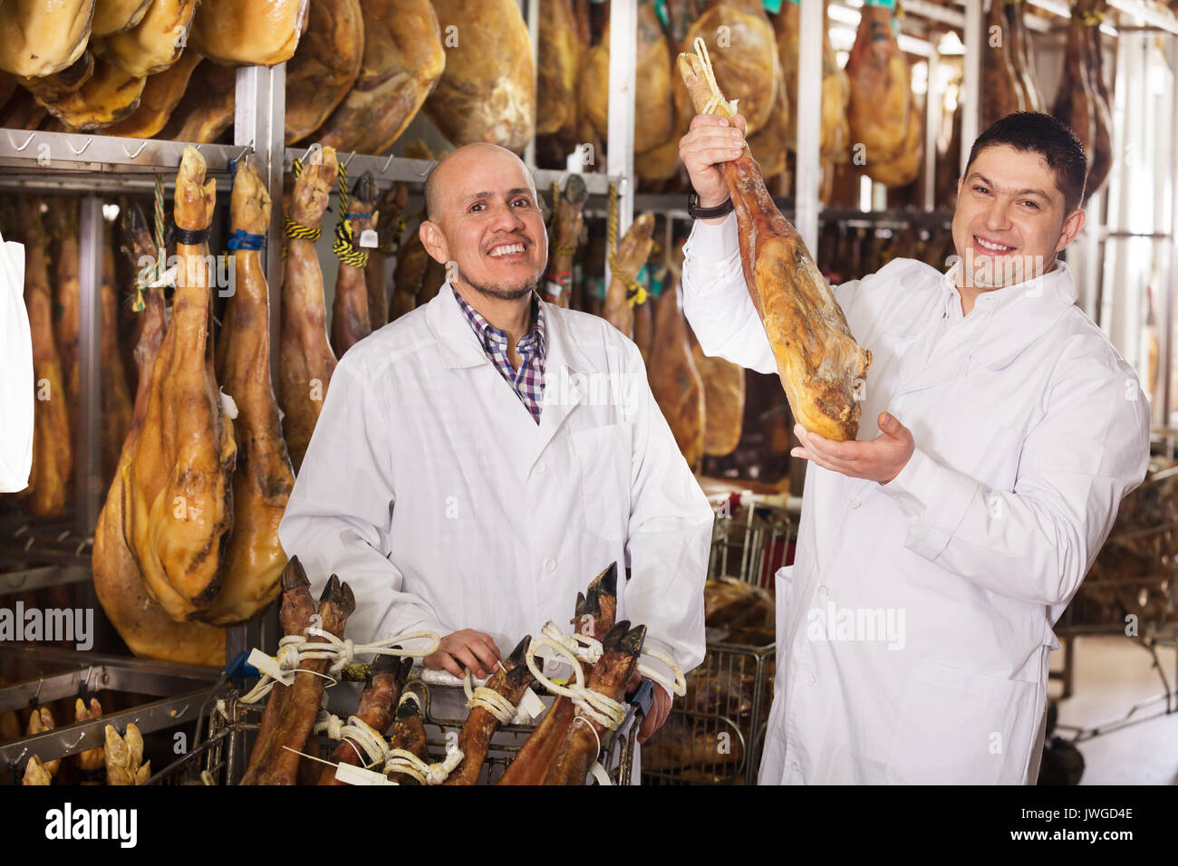 Mature butcher and his young assistant with jamon joints at the meat ...