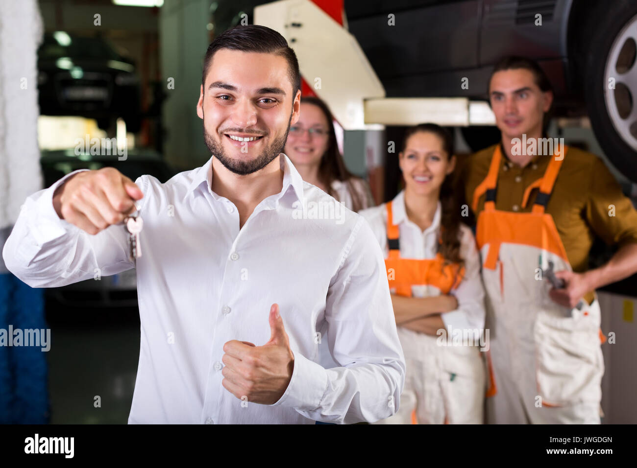 Happy smiling male client holding keys from his car and showing thumbs ...