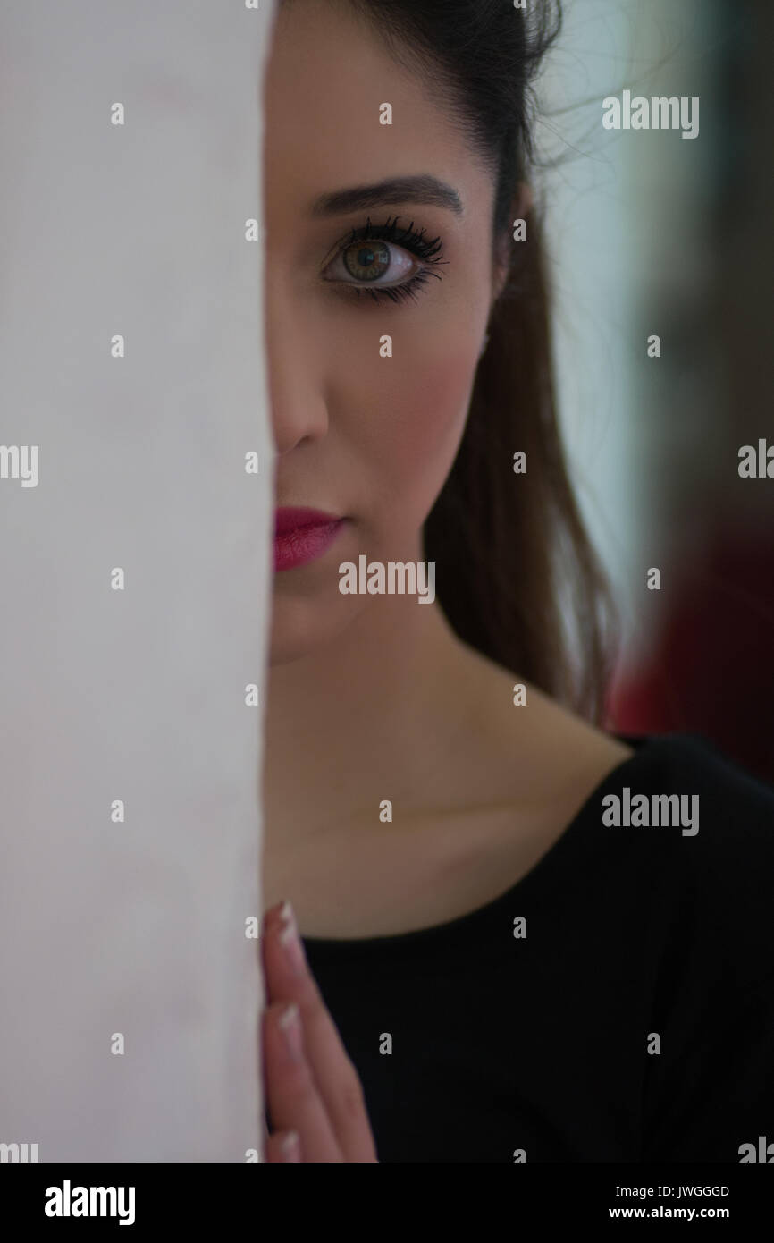 Scared young Asian woman hiding behind wall Stock Photo - Alamy
