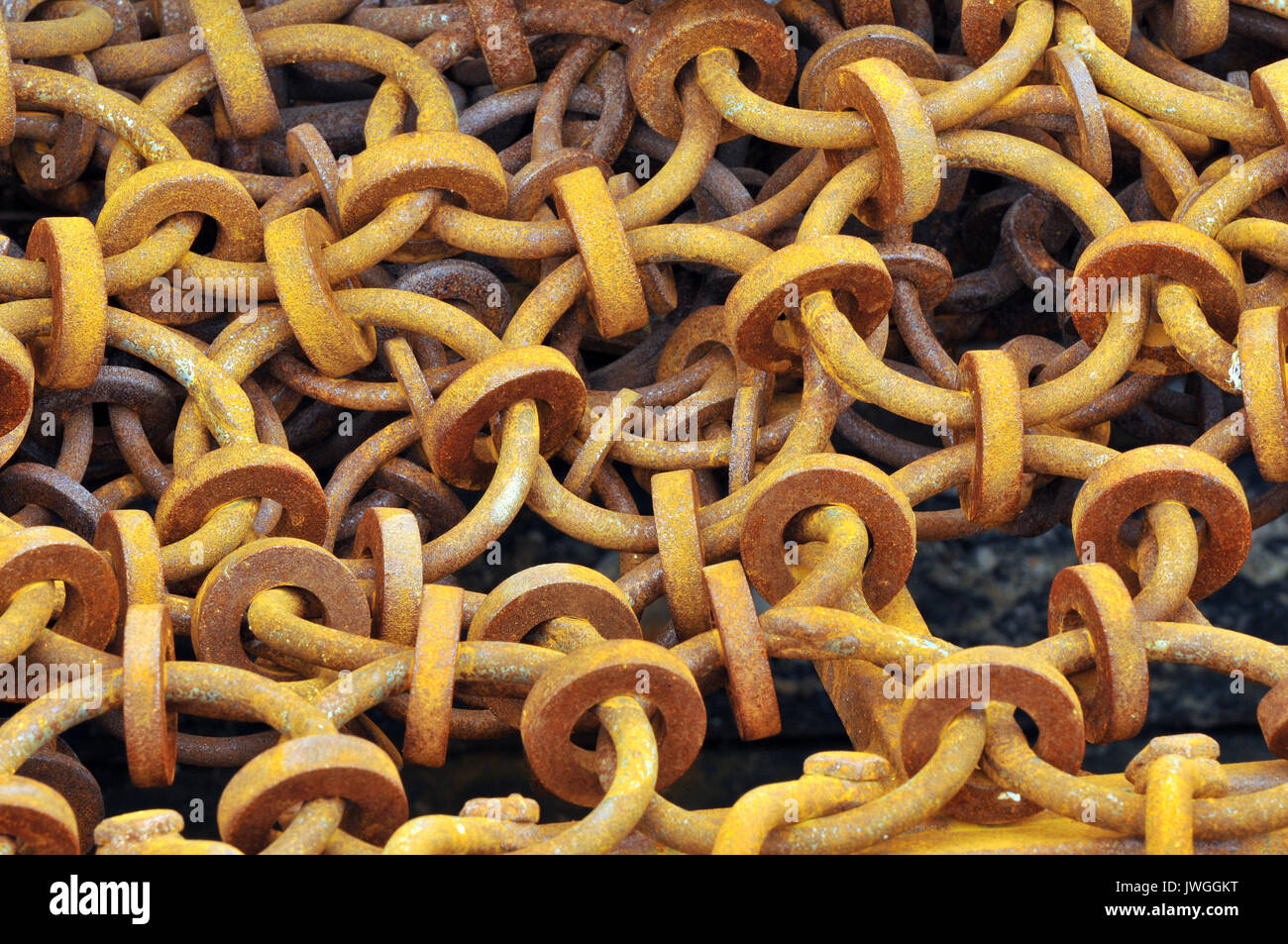 A pile of rust old metal chain links in a heap on the harbour side at ...
