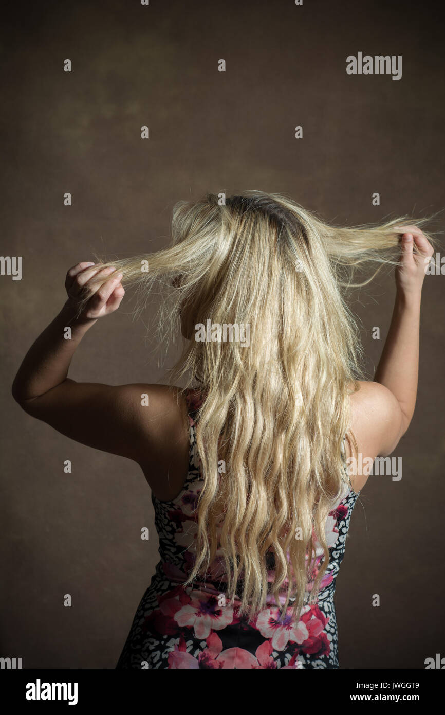 Rear view of a young blond woman hands on hair Stock Photo - Alamy