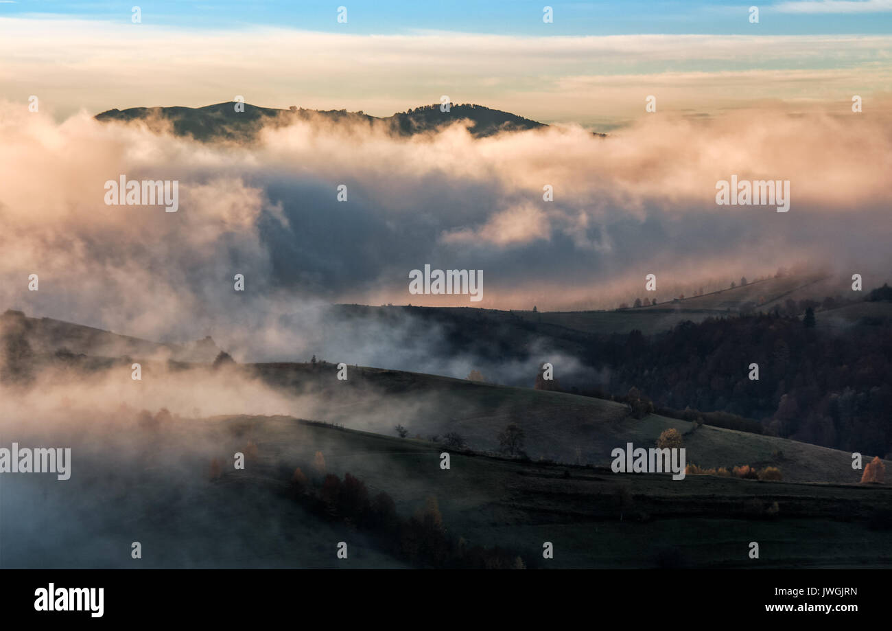 clouds and fog rising over countryside. rural fields on hills in ...