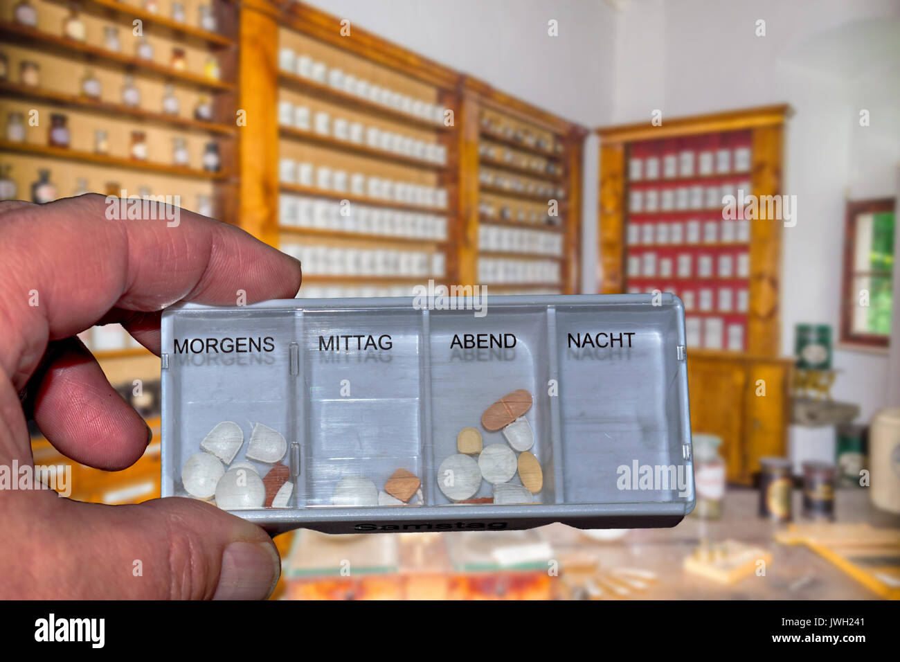 Pharmacist holding a tablet tin with medication in hand. In the ...