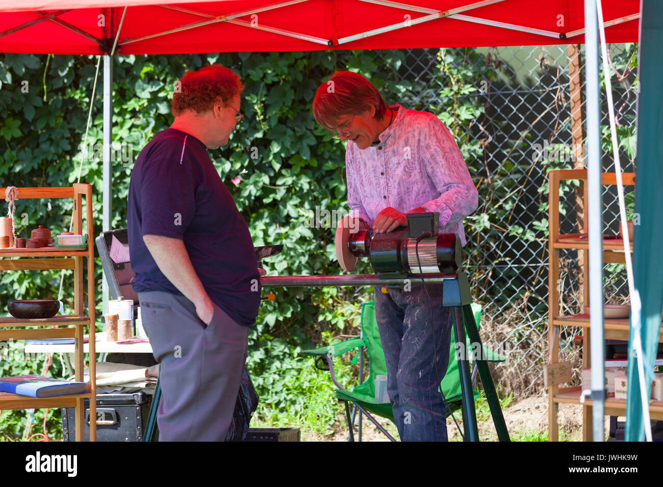 Onlooking man with glasses views another man with grinding wheel under ...