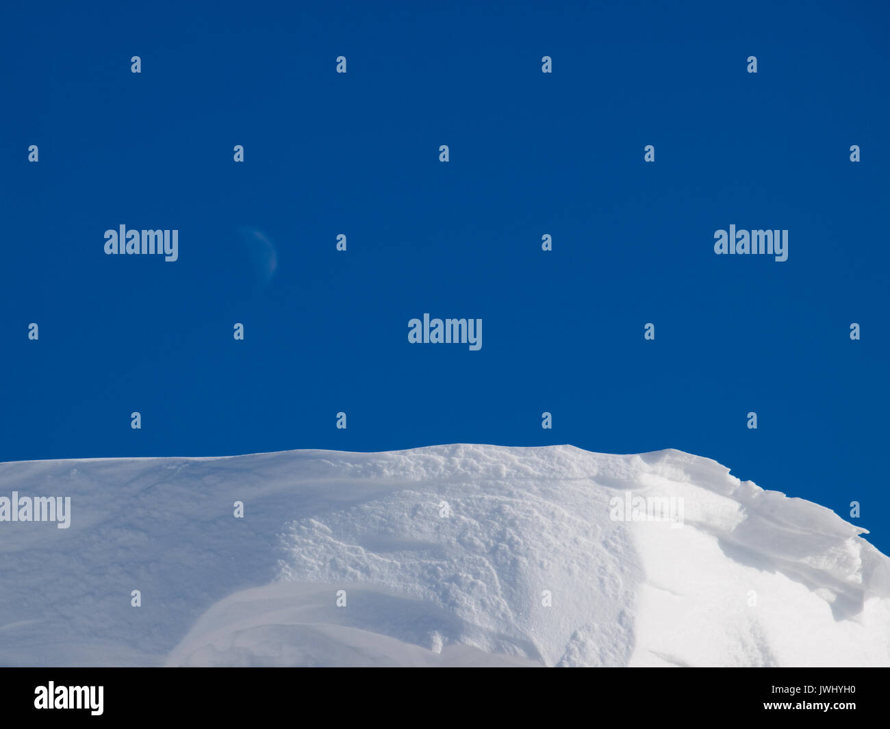 Pile of snow in front of blue sky and moon Stock Photo - Alamy
