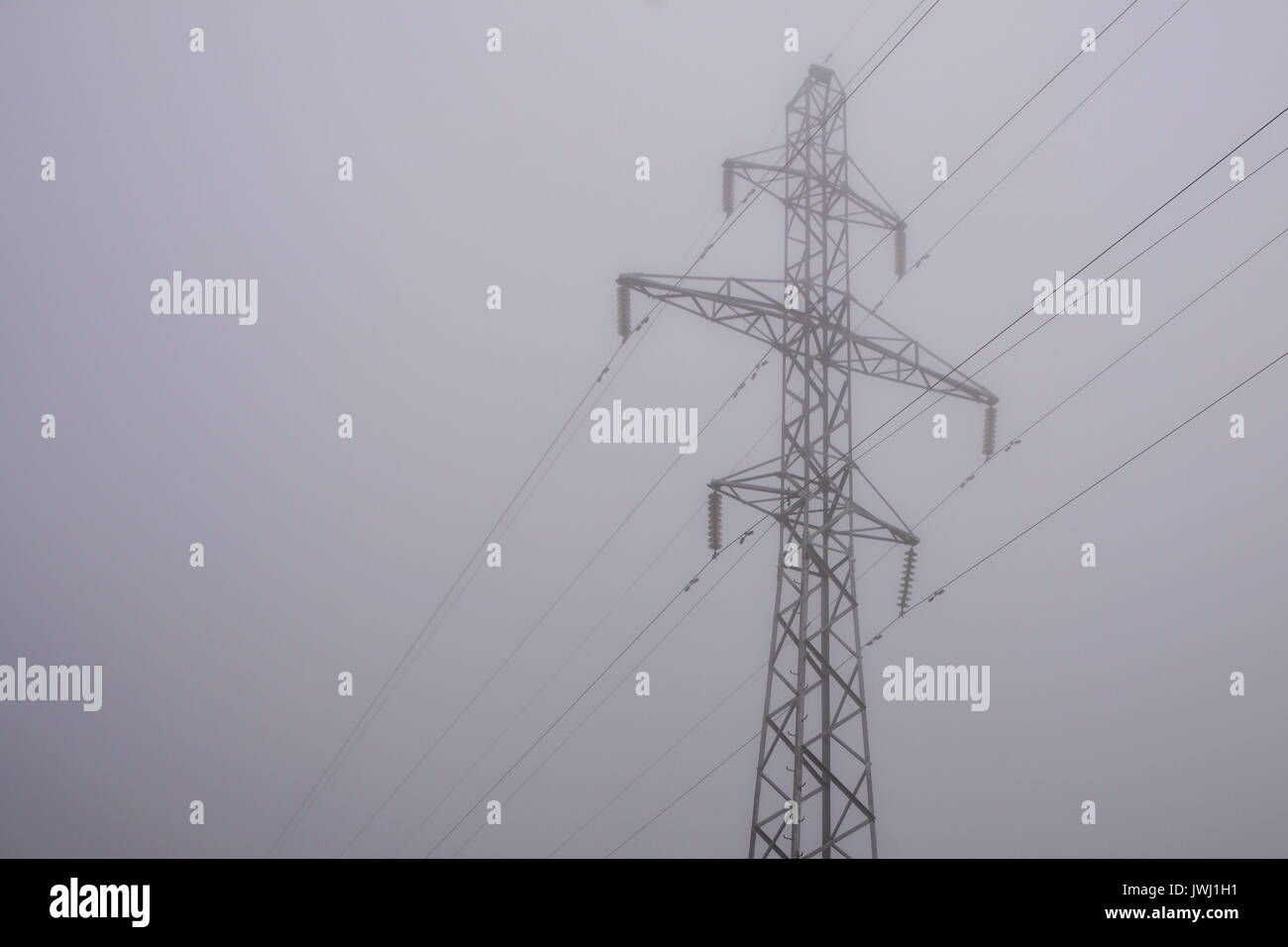 electric pylon and power line in morning fog. Dim world in obscure ...
