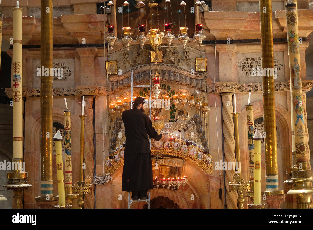 A Greek Orthodox clergyman lights sanctuary lamps at the entrance to ...
