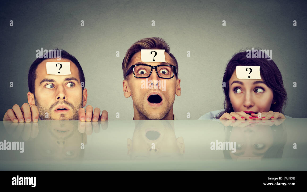 Scared young people two men and a woman with question mark hiding ...