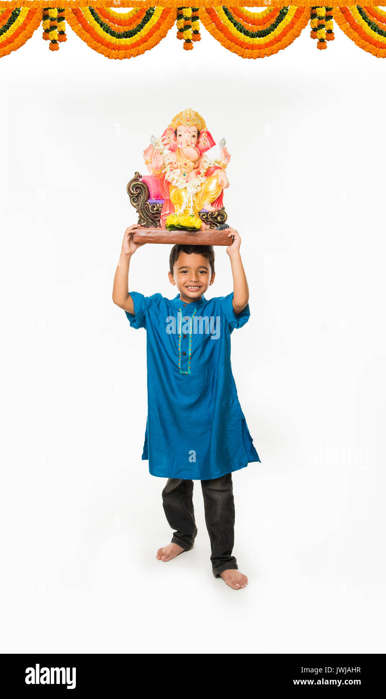 Portrait of cute little Indian boy holding a Ganesh idol or lord ...