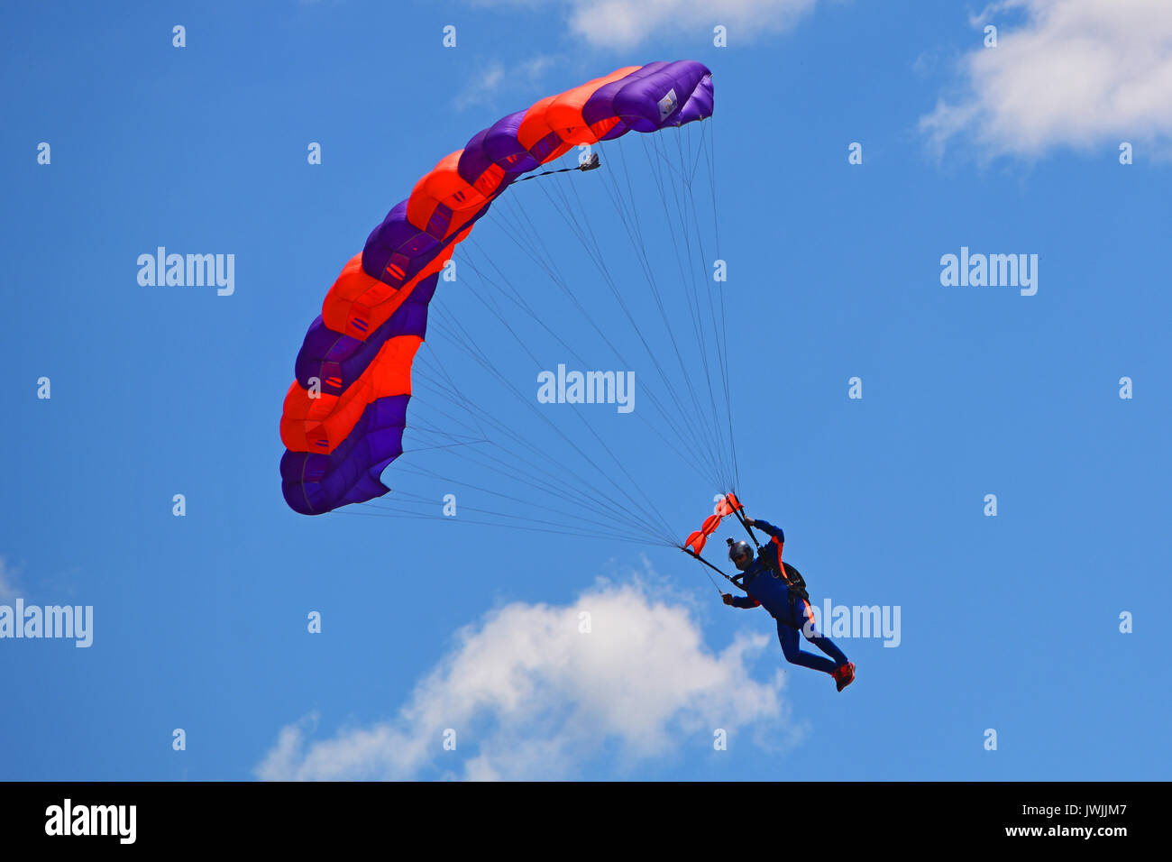 Colorful parachute against blue sky and white feathery clouds ...
