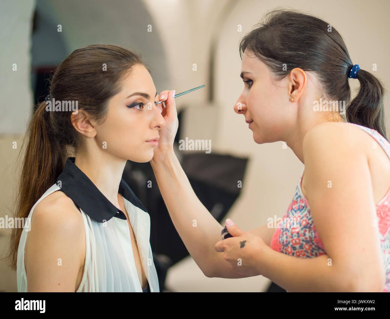 Makeup artist makes models eye makeup. Beautiful woman applying ...