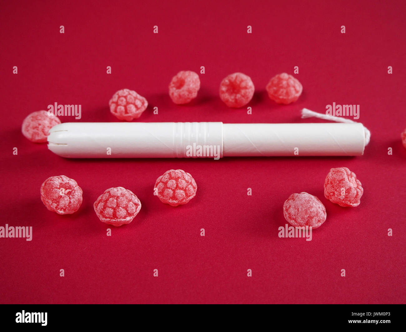 Tampon with red candies on red background Stock Photo - Alamy