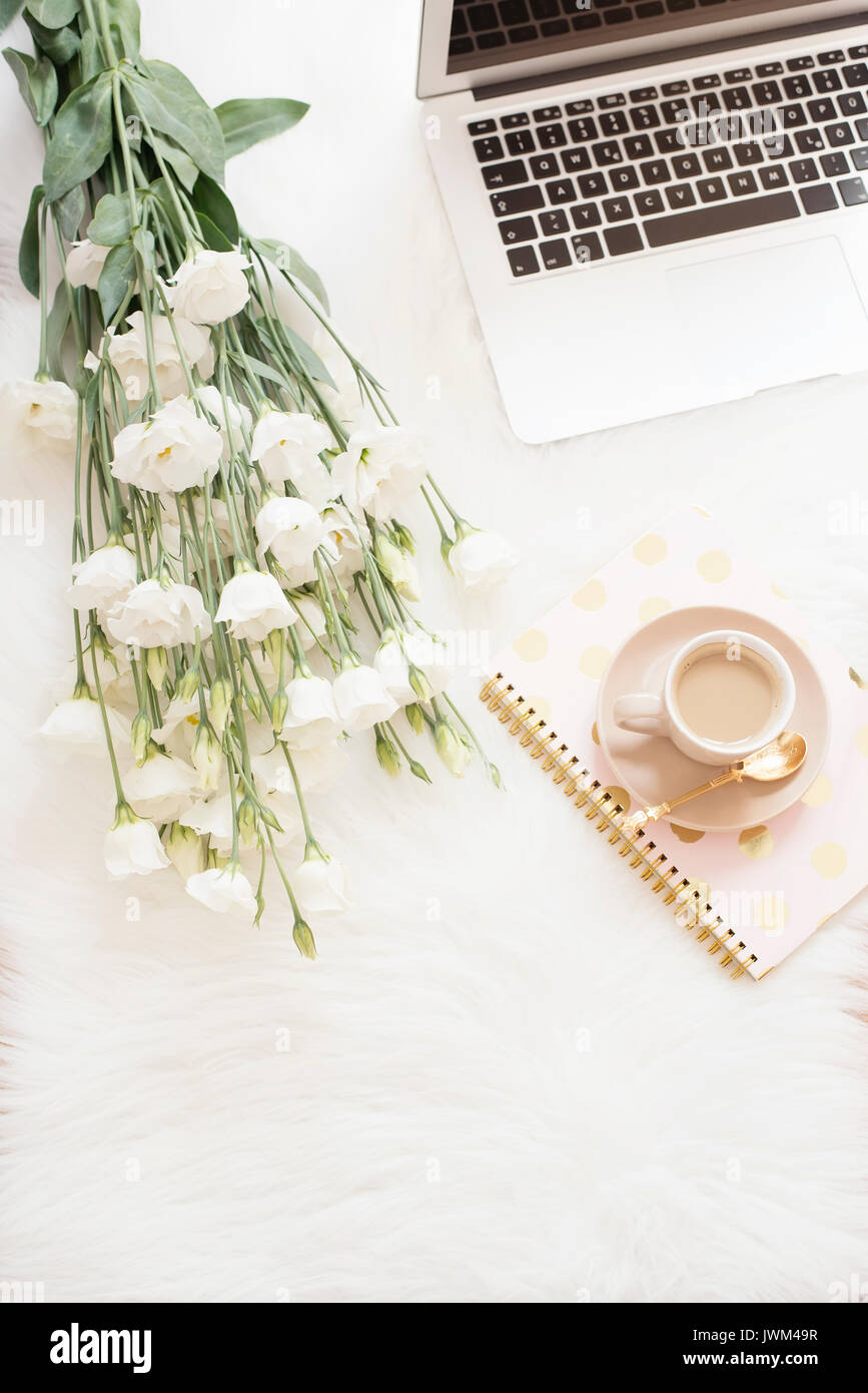 Laptop, coffee, notebook and a large bouquet white flowers on the floor ...