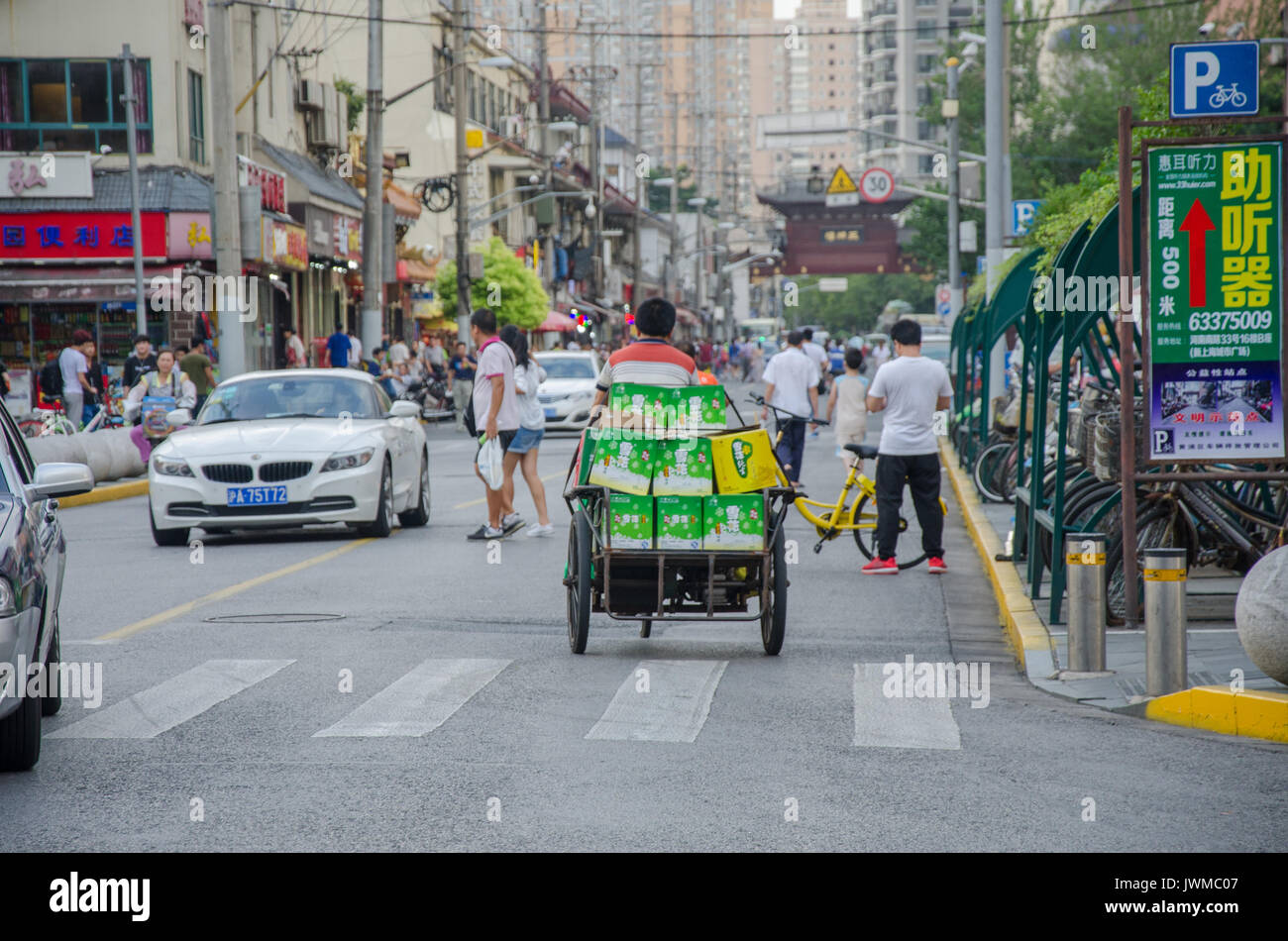 A man rides a tricycle loaded with boxes along a bust road in shanghai ...