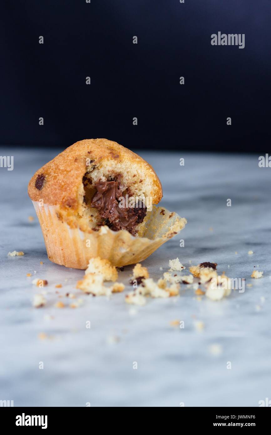 Half eaten vanilla muffin with cocoa filling and chocolate chips on ...
