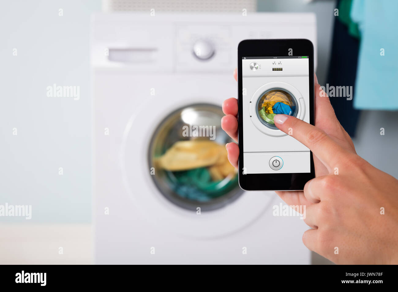 Close-up Of Person Hand Operating Washing Machine Using Mobile Phone ...