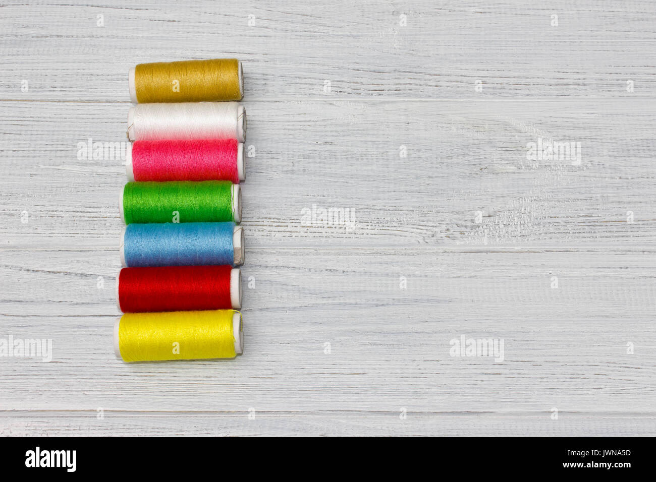 Bobbins with colorful threads on old wooden table background Stock ...