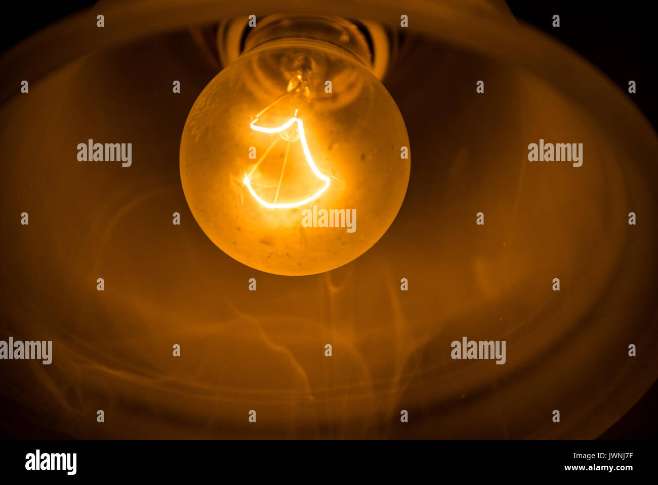 Glowing element of an incandescent light bulb illuminated in a hanging ...