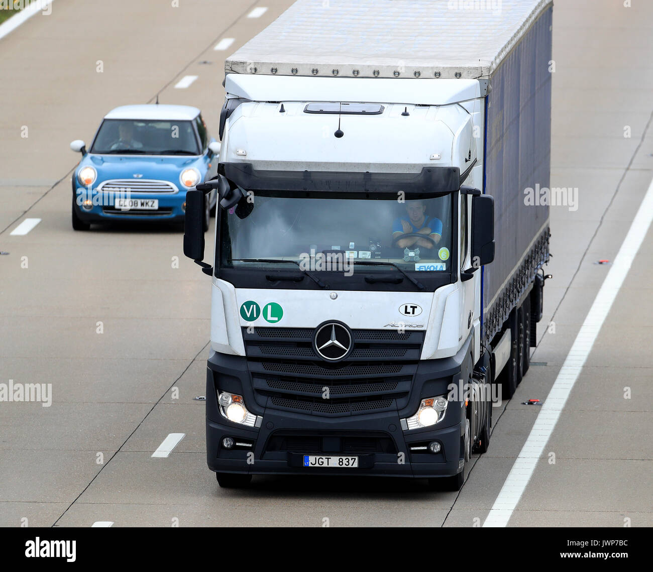 A lorry driver steers his vehicle using his elbows as he drives along ...