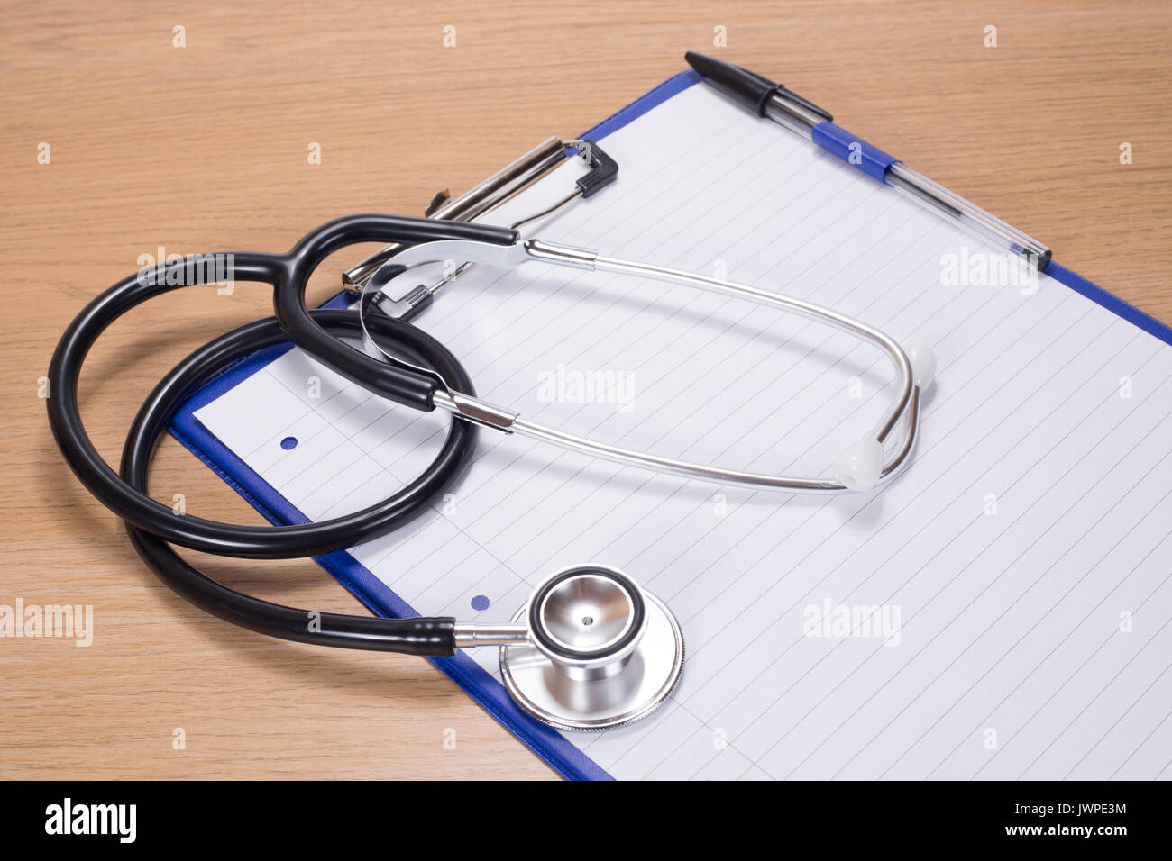Stethoscope lying on a blank page of lined paper attached to a ...