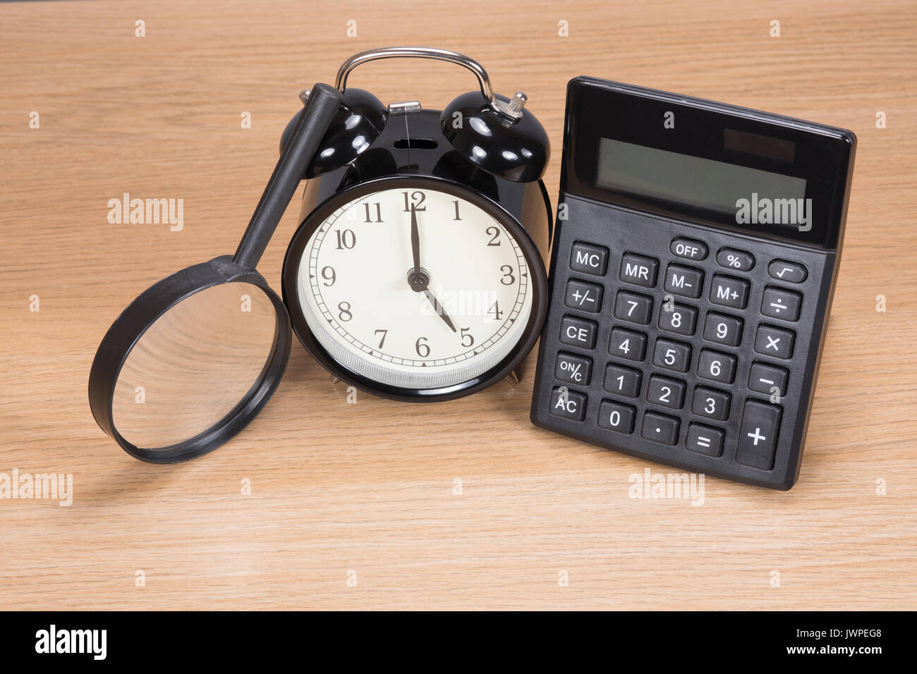 High angle view of alarm clock between magnifying glass and calculator ...