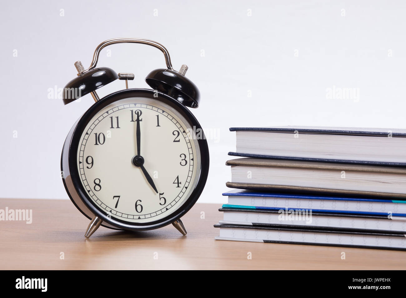 Alarm clock alongside a stack of books or office journals and a diary ...