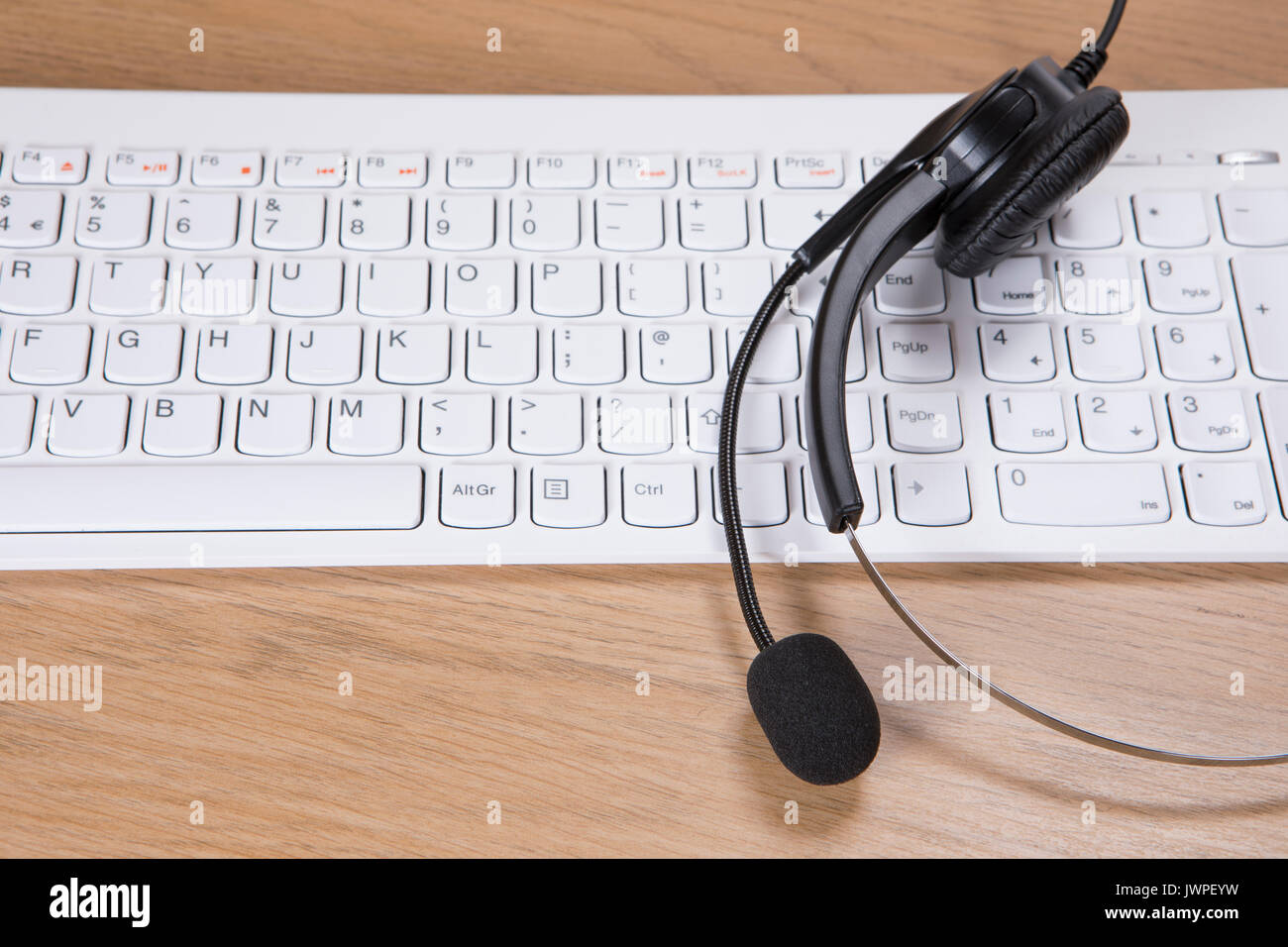 Headset and computer keyboard on desk in a close up cropped view ...